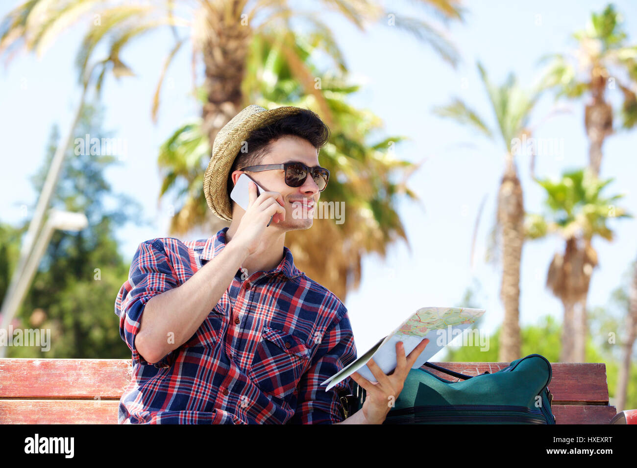 Portrait of a smiling young man holding map and asking for direction on ...