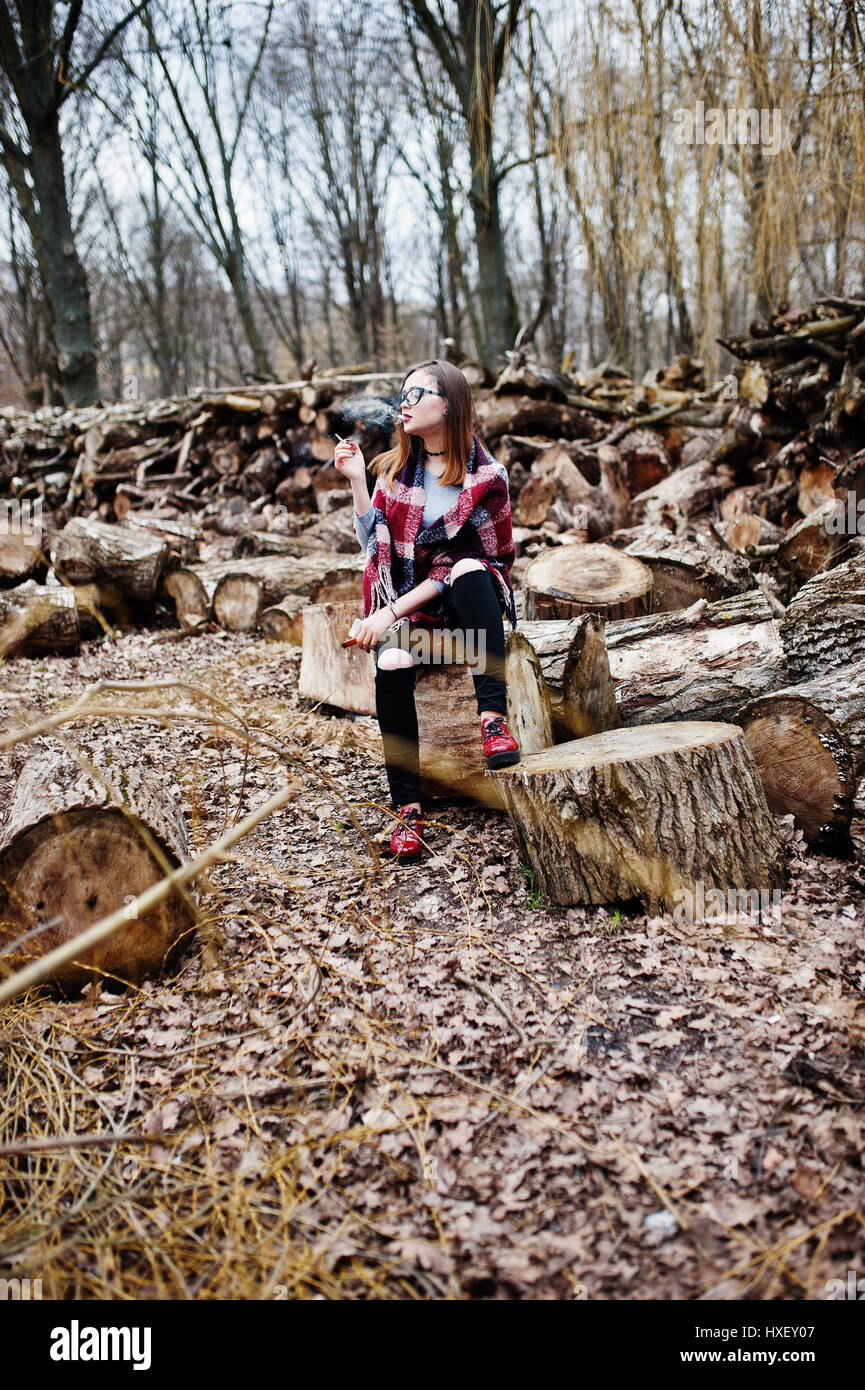 Young girl smoking cigarette outdoors background wooden stumps. Concept ...