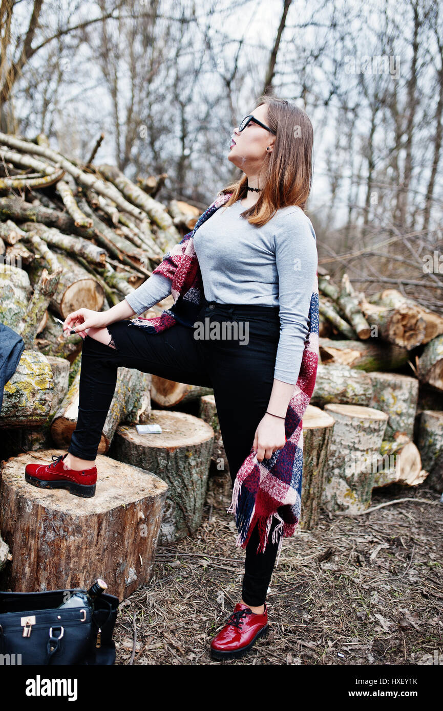 Young drunk girl smoking cigarette outdoors background wooden stumps ...