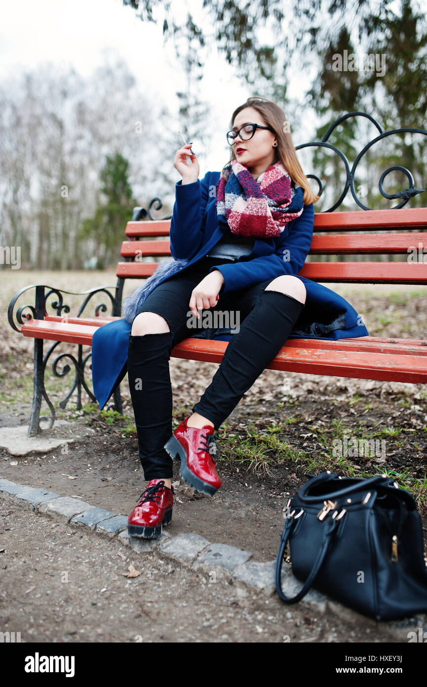 Young girl smoking cigarette outdoors sitting on bench. Concept of ...