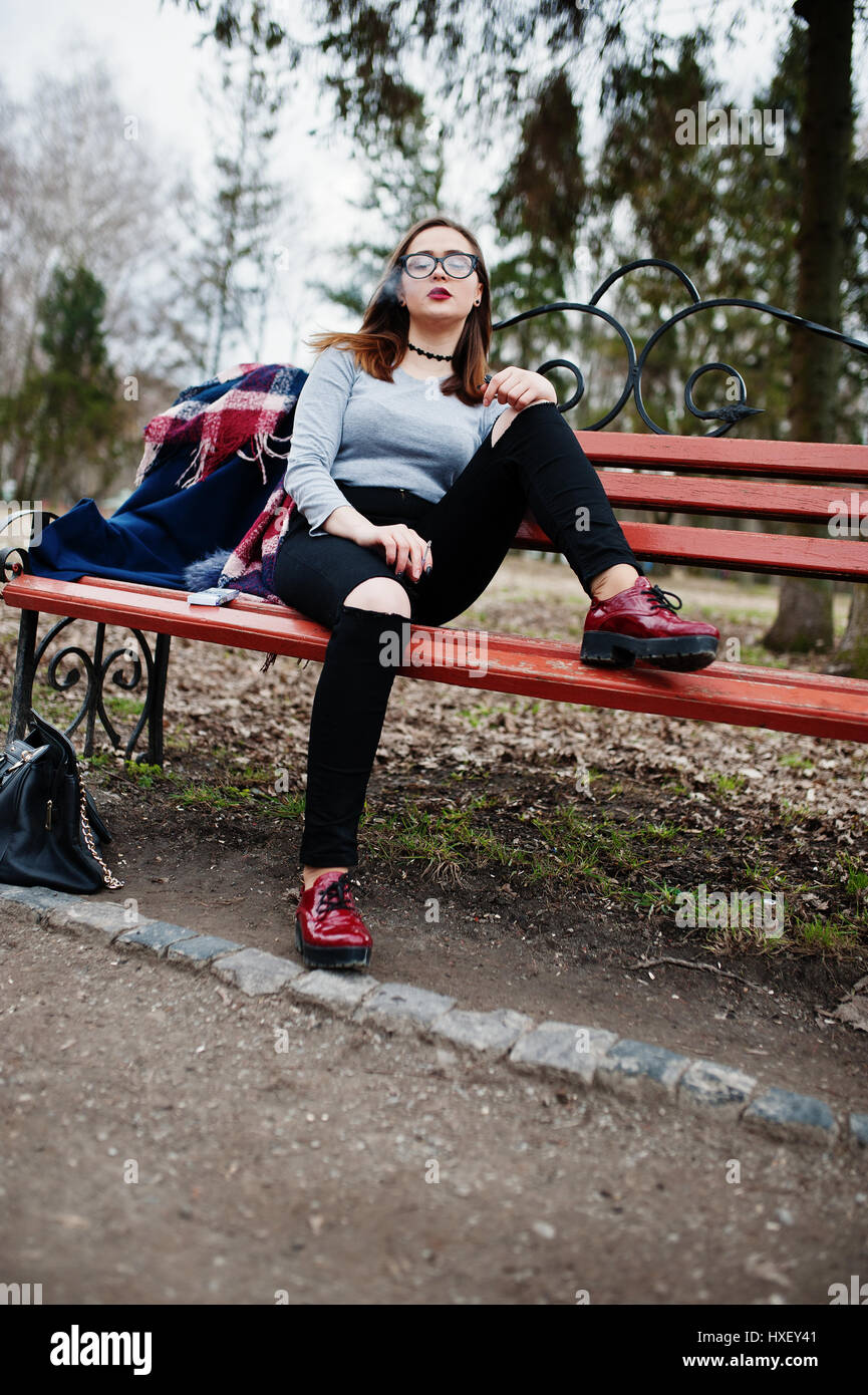 Young girl smoking cigarette outdoors sitting on bench. Concept of ...