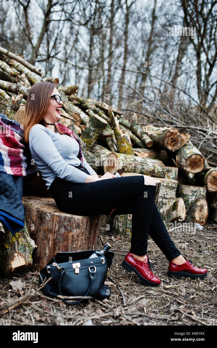 Young drunk girl smoking cigarette outdoors background wooden stumps ...