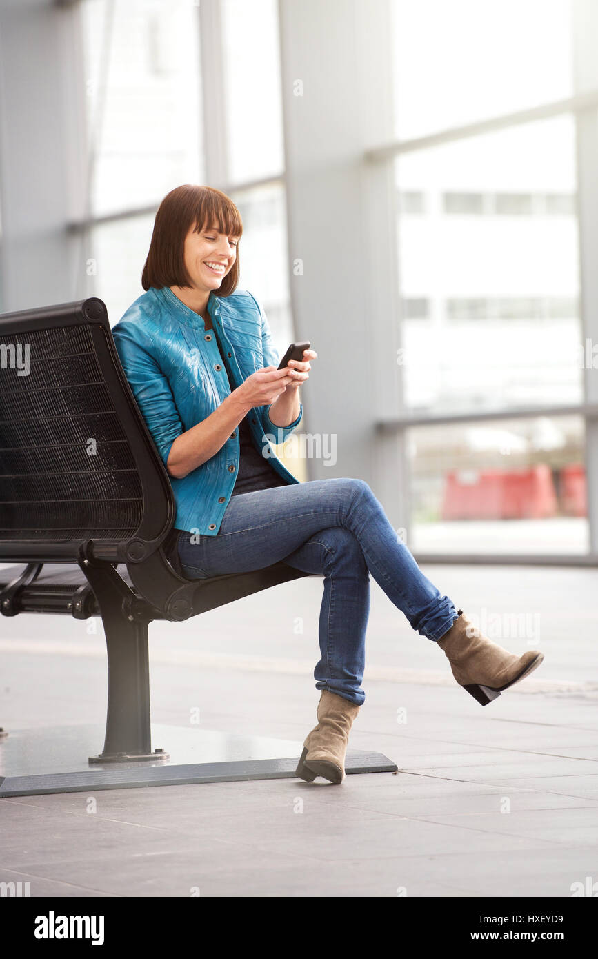 Portrait of an attractive older woman sitting and using mobile phone ...