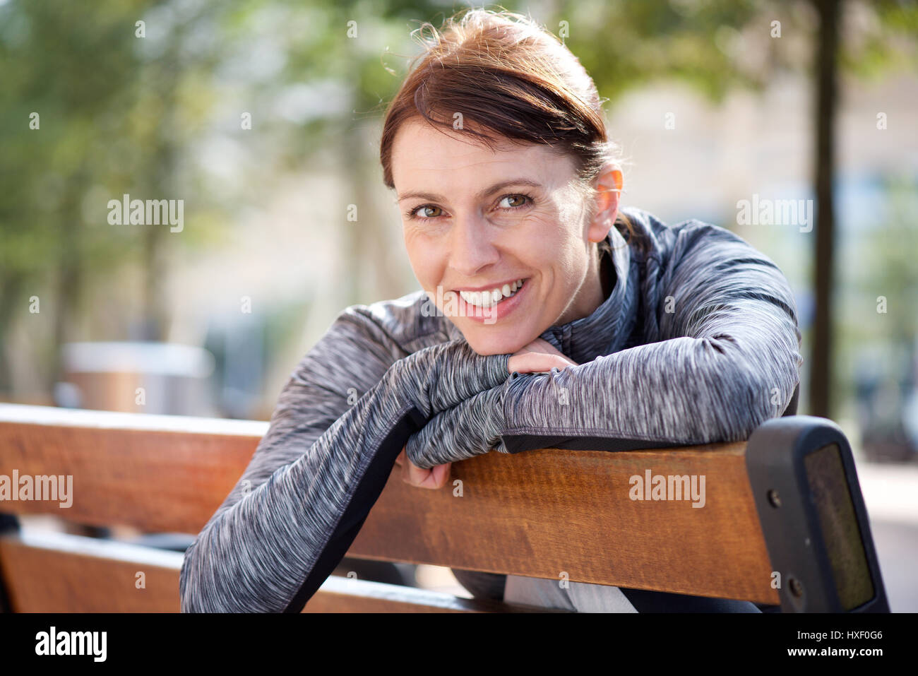 Portrait of a smiling sports woman relaxing outside on bench Stock ...