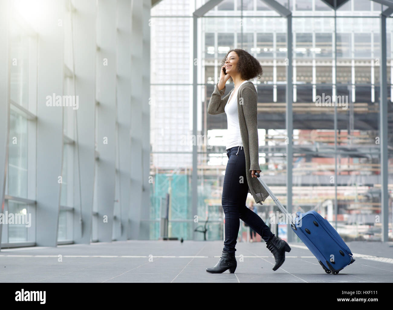 Full length side portrait of a traveling young woman with mobile phone ...