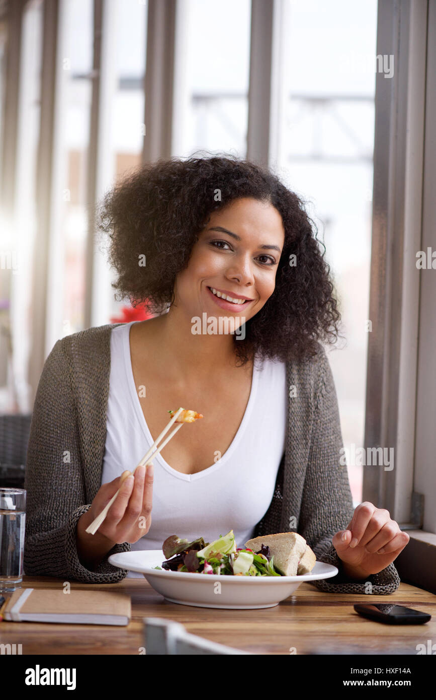 Portrait of a smiling african american woman in restaurant eating salad ...
