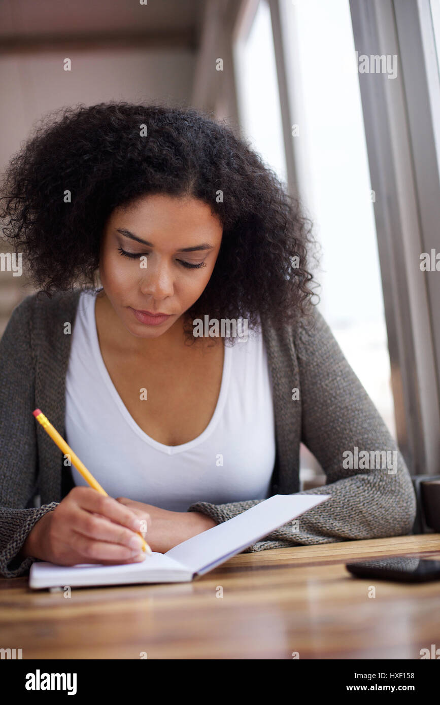 Close up portrait of a young african american female student writing in ...