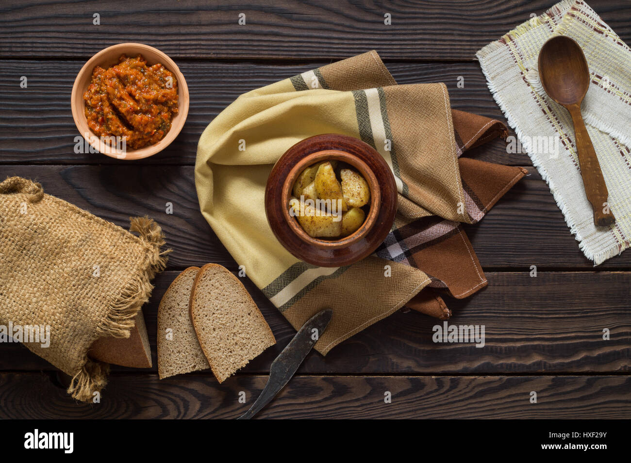 Baked potatoes in a clay pot, bread and sauce on wooden table Stock ...