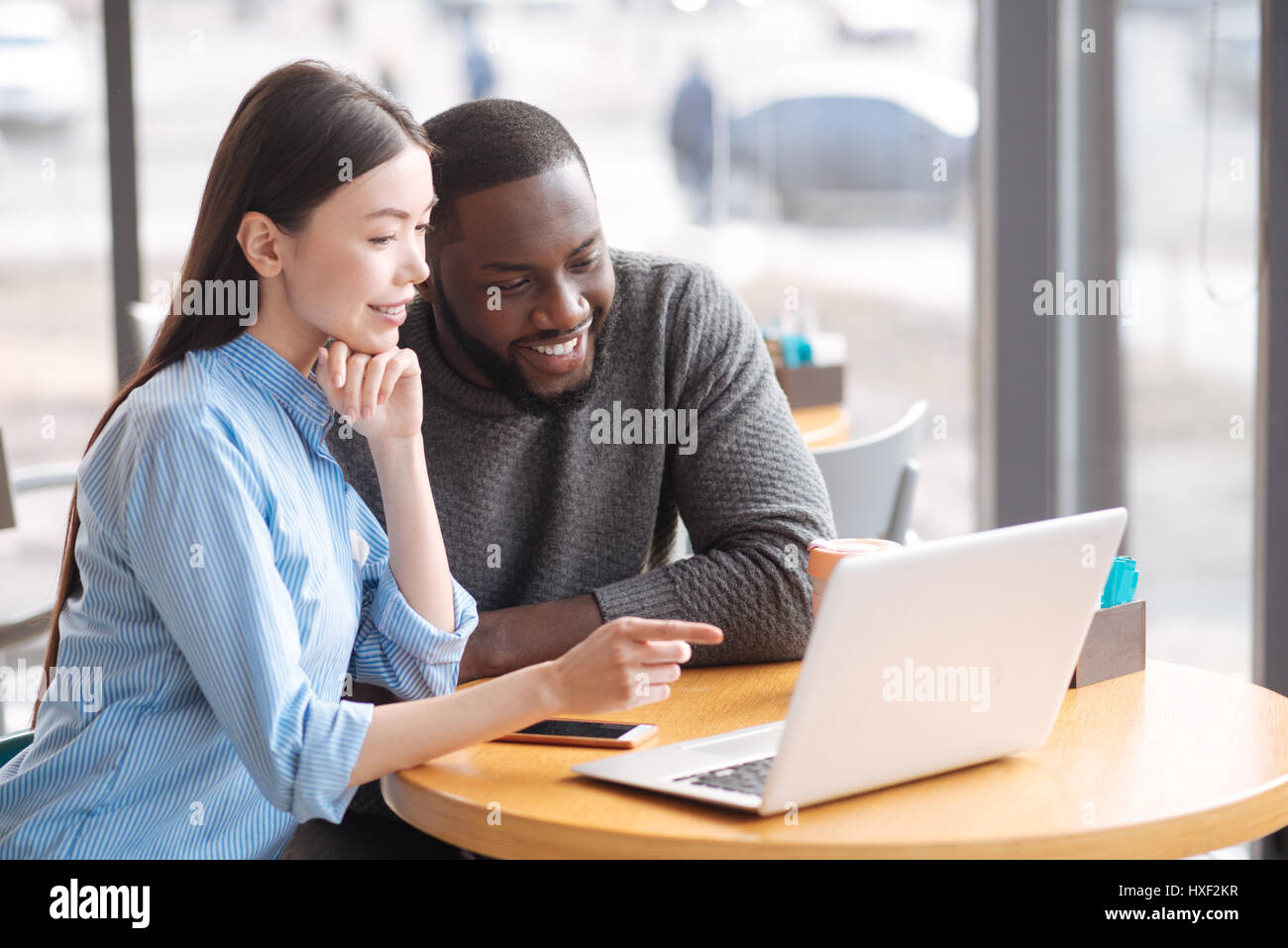 Nice couple using laptop near window Stock Photo - Alamy