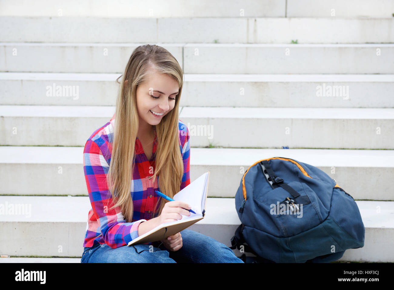 Portrait of a smiling girl sitting outside writing in book Stock Photo ...