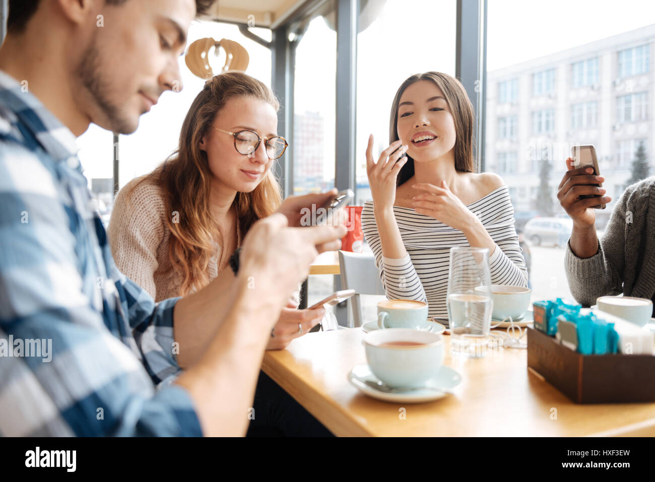 Friends using smartphones in the cafe Stock Photo - Alamy