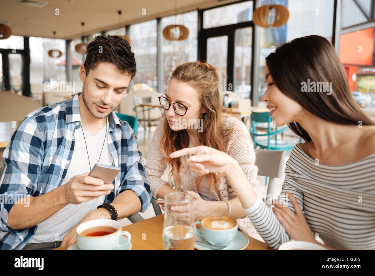 Friends using smartphones together Stock Photo - Alamy