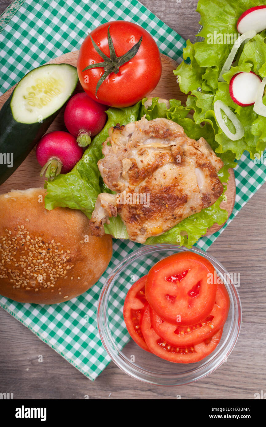Preparing delicious homemade chicken burger with fries, fresh lettuce ...