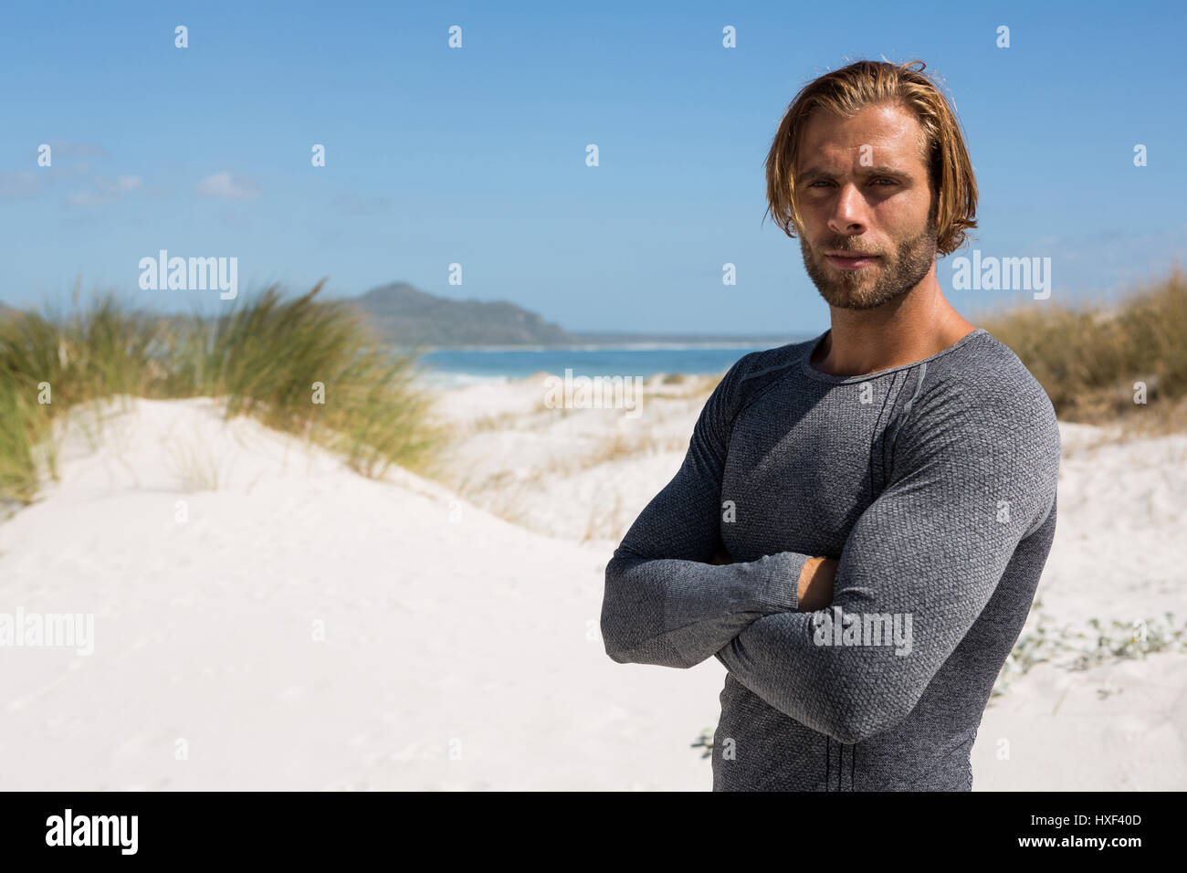 Portrait of confident athlete standing at beach against sky Stock Photo ...
