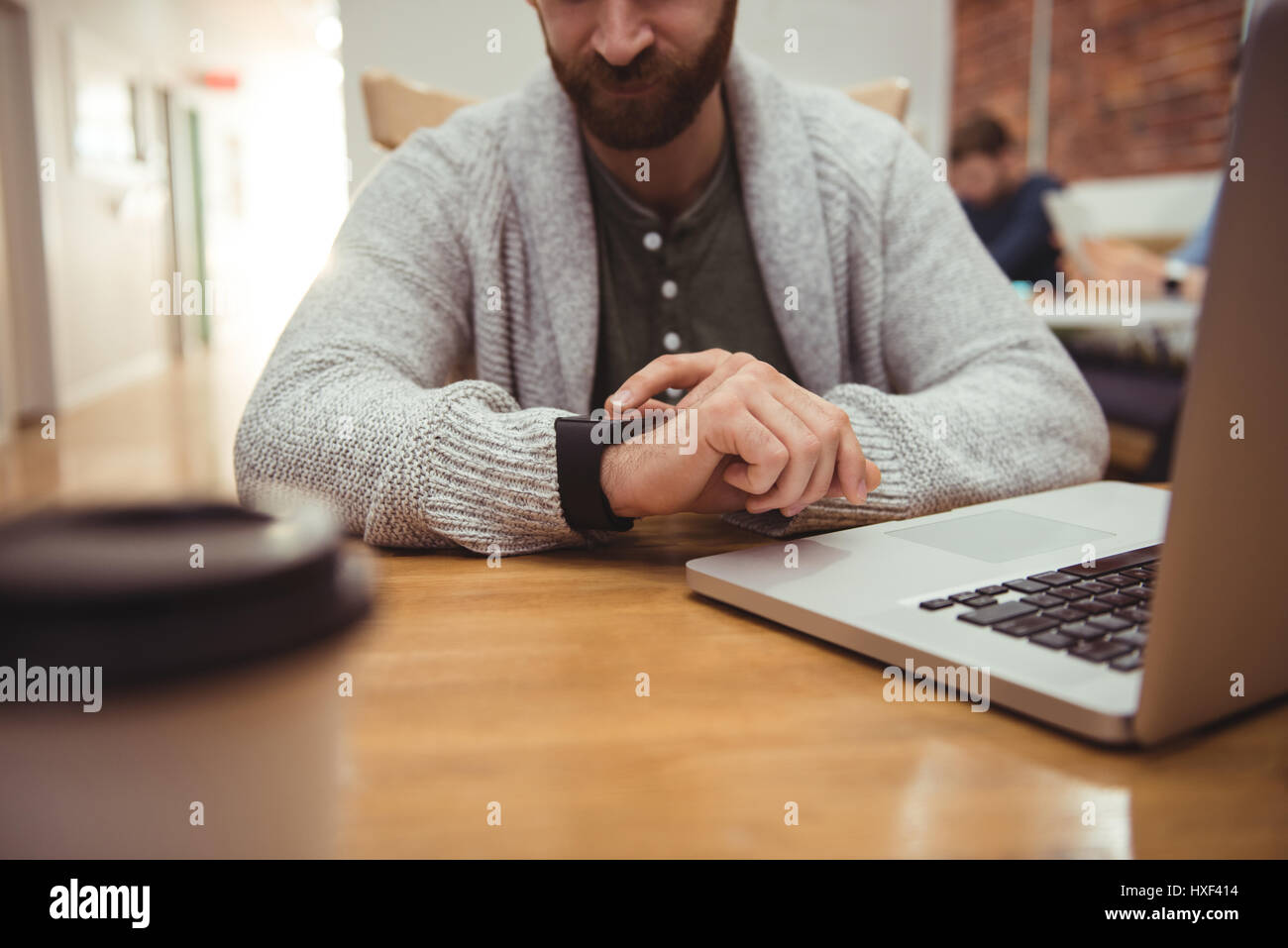Male executive using smartwatch at desk in office Stock Photo - Alamy
