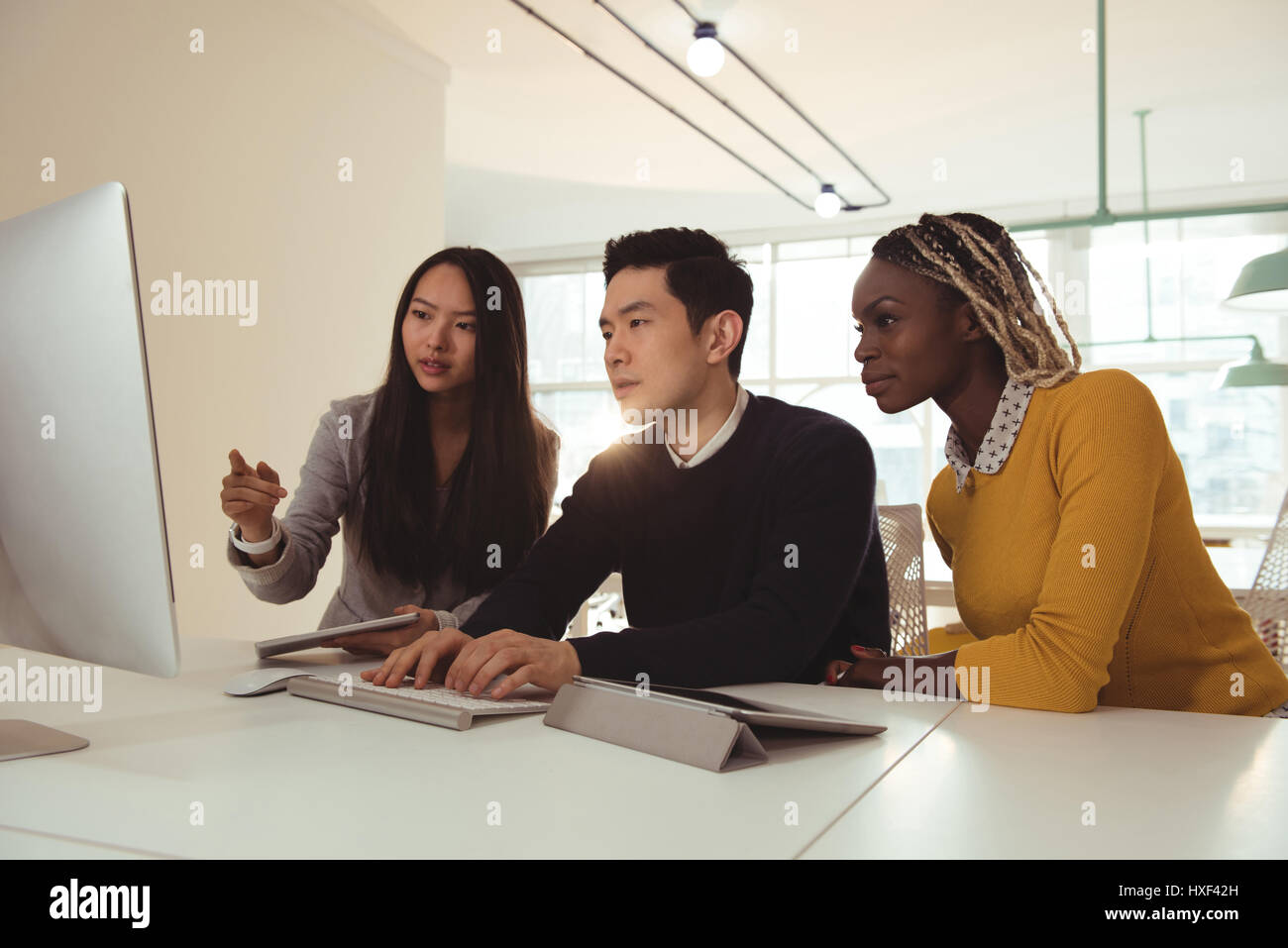Group of executives discussing over computer at desk in office Stock ...