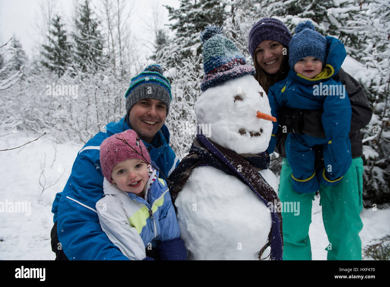 Portrait of happy parents and children with snowman on beautiful snowy ...