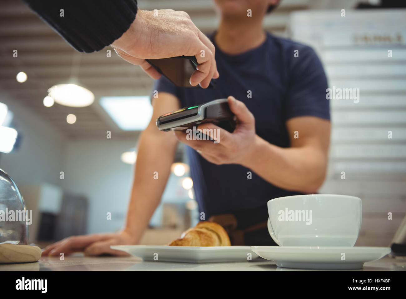 Customer making contactless payment with smartphone in coffee shop ...