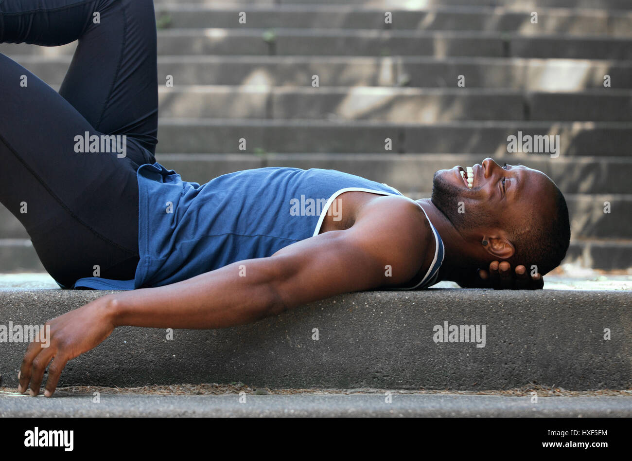 Smiling young man lying down on back outside Stock Photo - Alamy