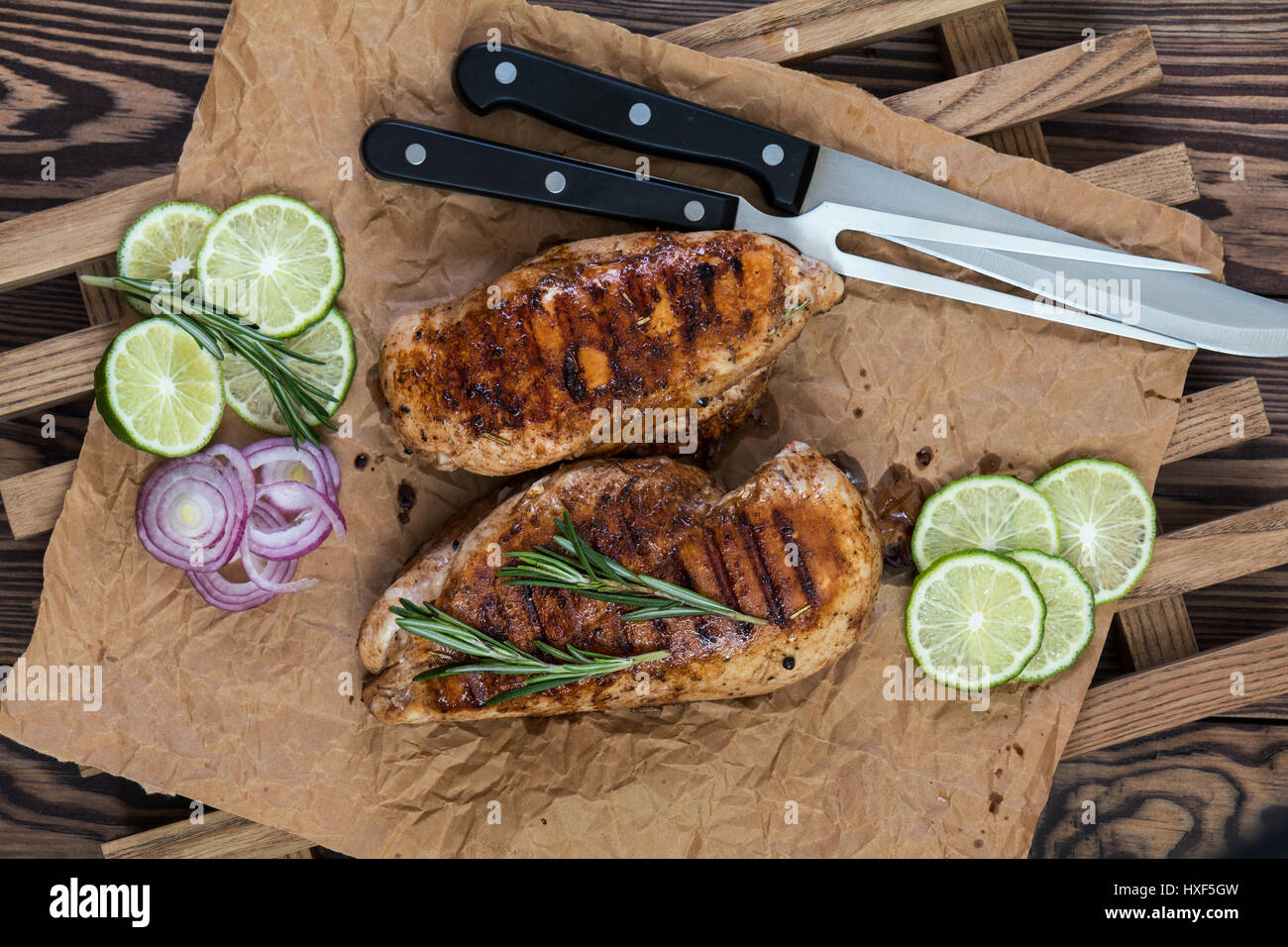 Grilled chicken filet with herbs on a paper on wooden background ...