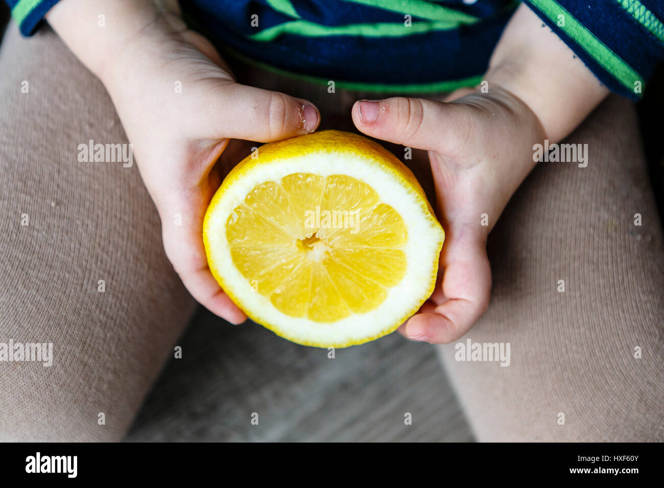 beautiful fresh yellow lemon in little cute kid hands and fingers on ...