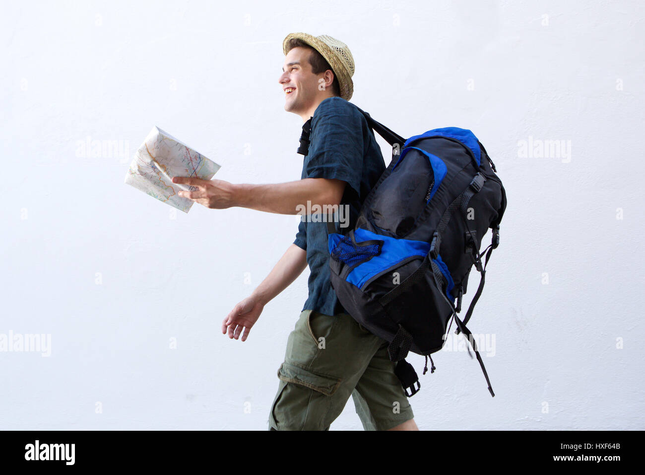 Side portrait of a smiling backpacker with map walking Stock Photo - Alamy