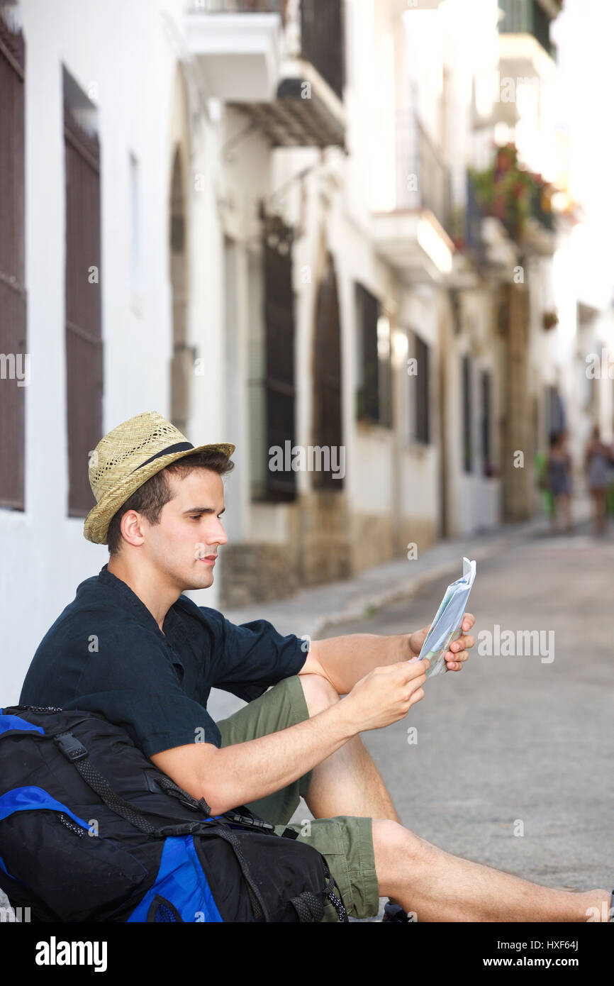 portrait of a travel man sitting on sidewalk reading map Stock Photo ...