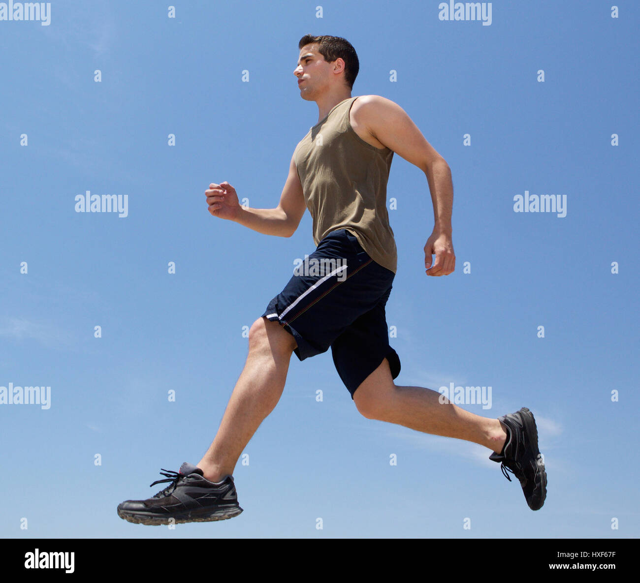 Sporty young man running outside with blue sky in background Stock ...