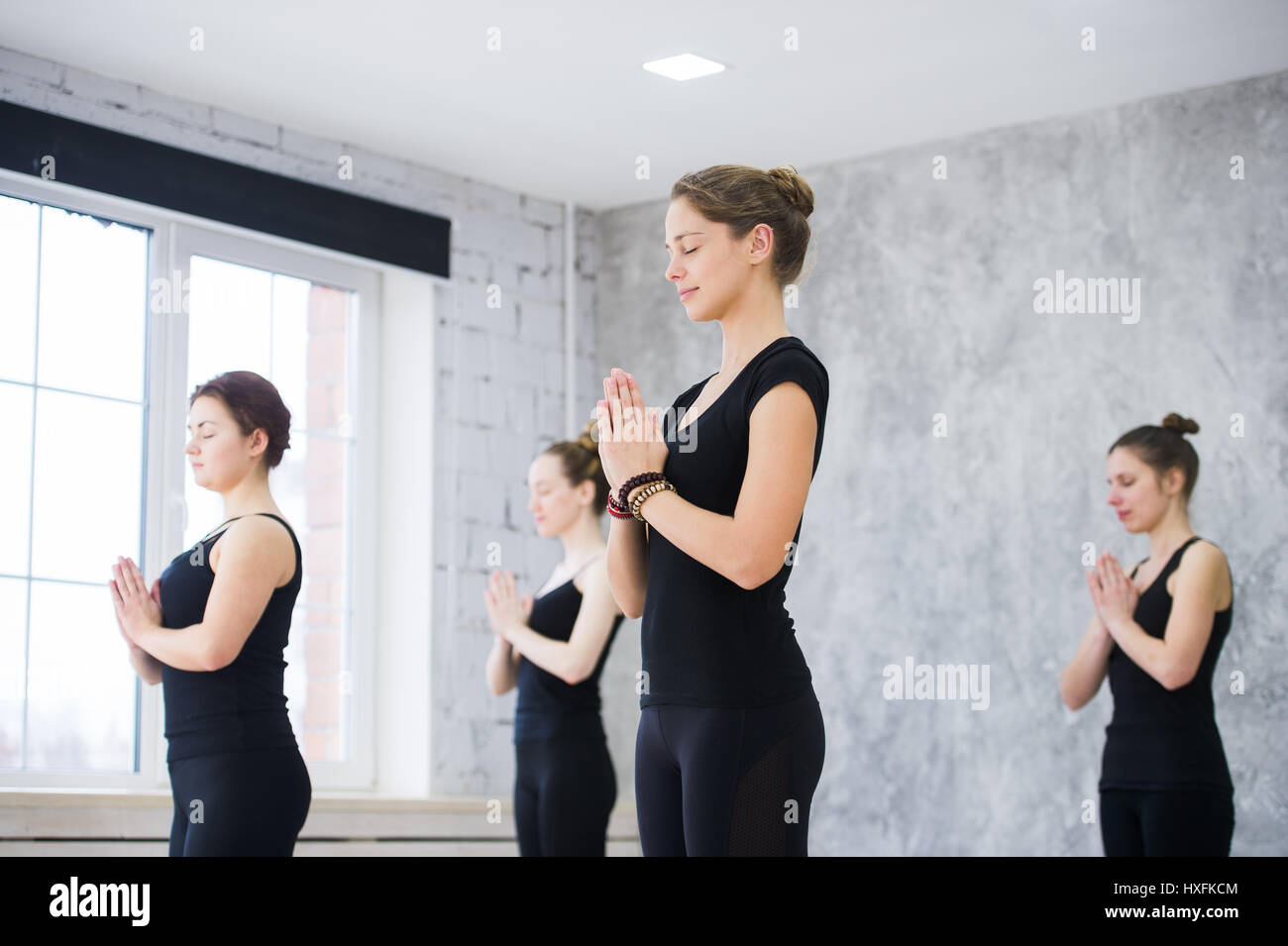 Female trainer with class standing in namaste pose at yoga class Stock ...