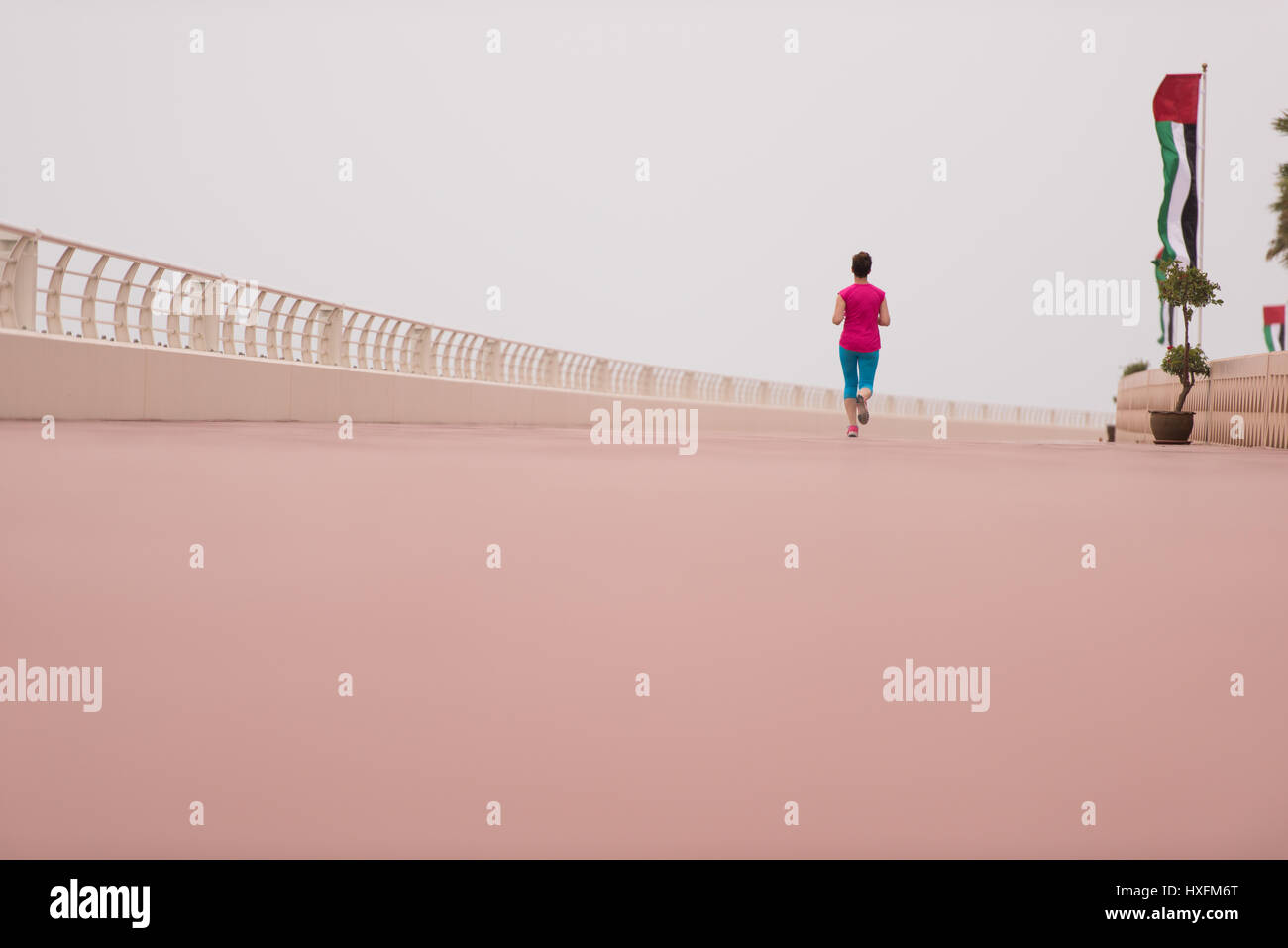 very active young beautiful woman busy running on the promenade along ...