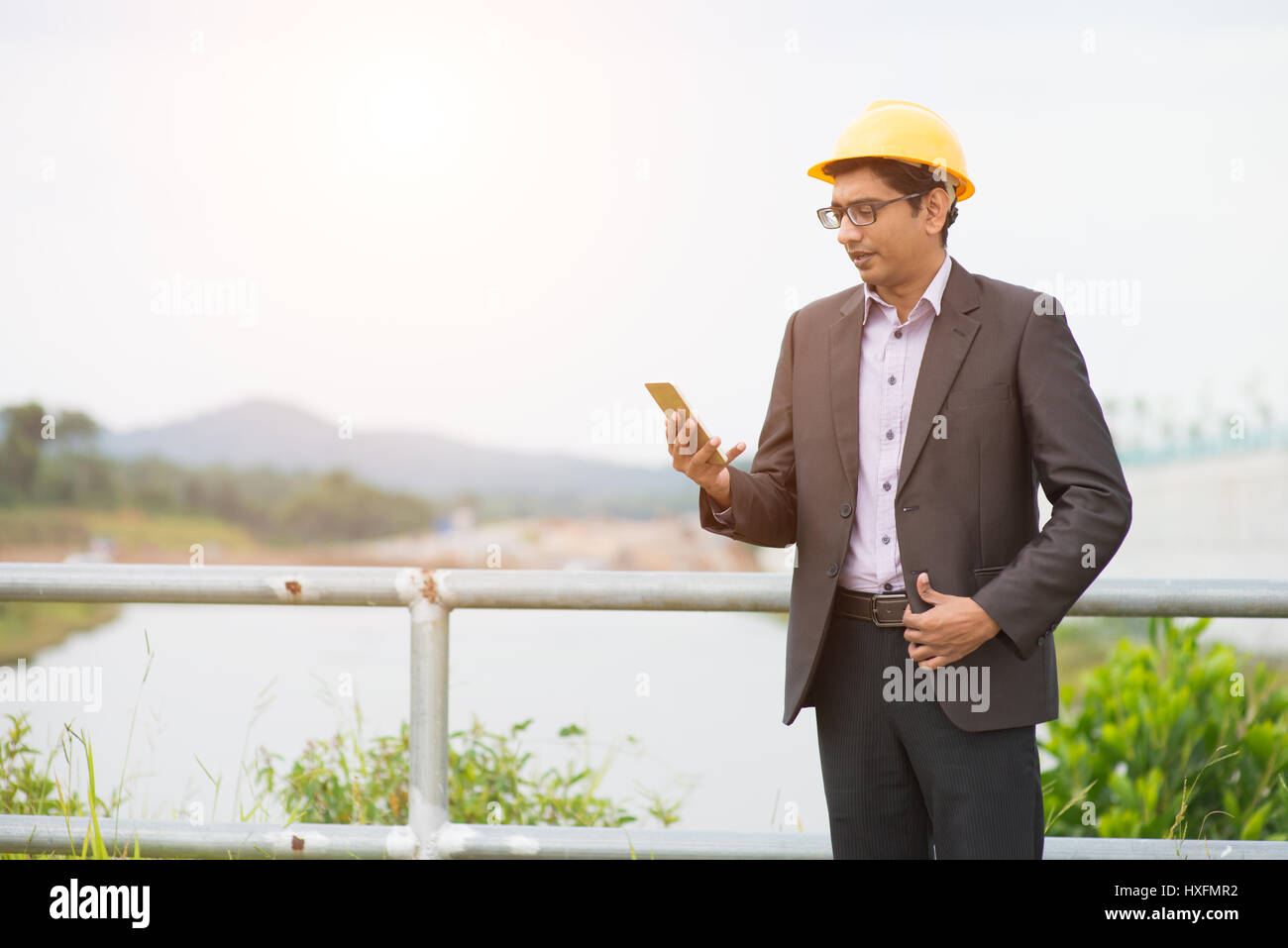 indian male engineer using phone on the lakeside Stock Photo - Alamy