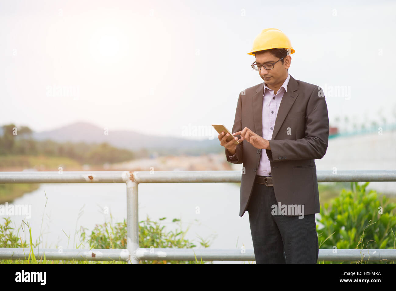 indian male engineer using phone on the lakeside Stock Photo - Alamy