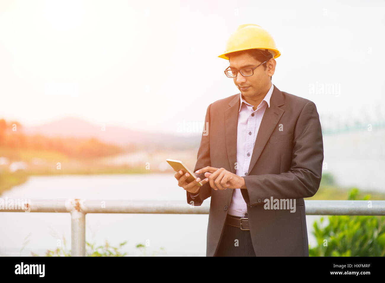 indian male engineer using phone on the lakeside Stock Photo - Alamy