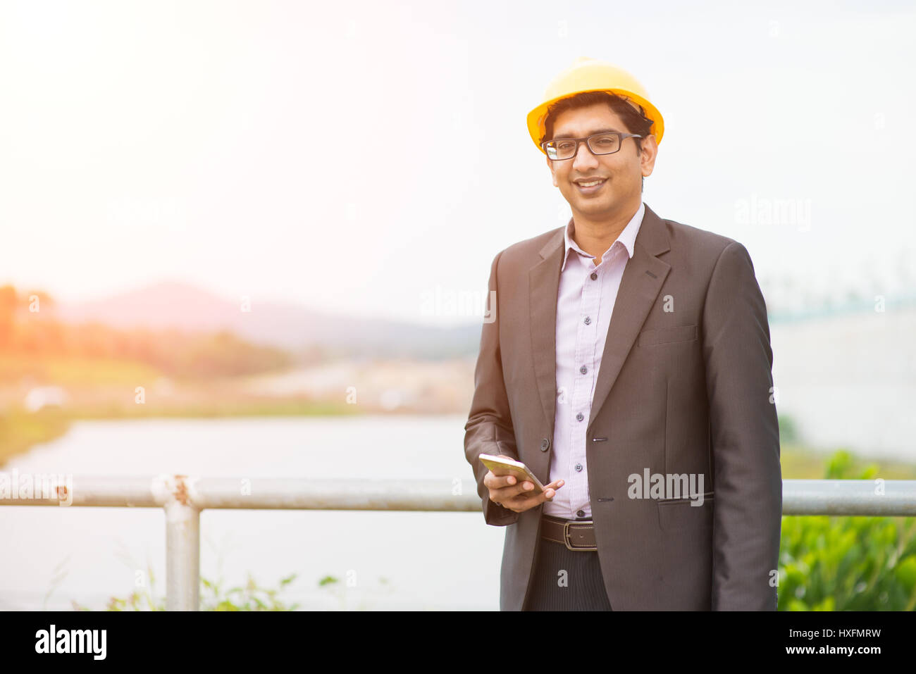 indian male engineer using phone on the lakeside Stock Photo - Alamy