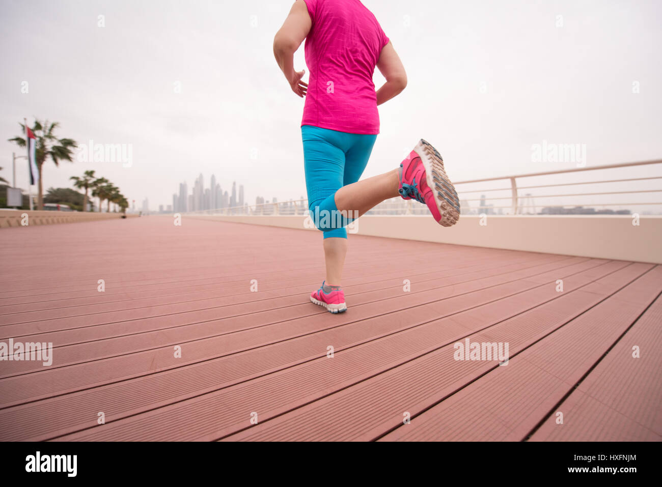 very active young beautiful woman busy running on the promenade along ...