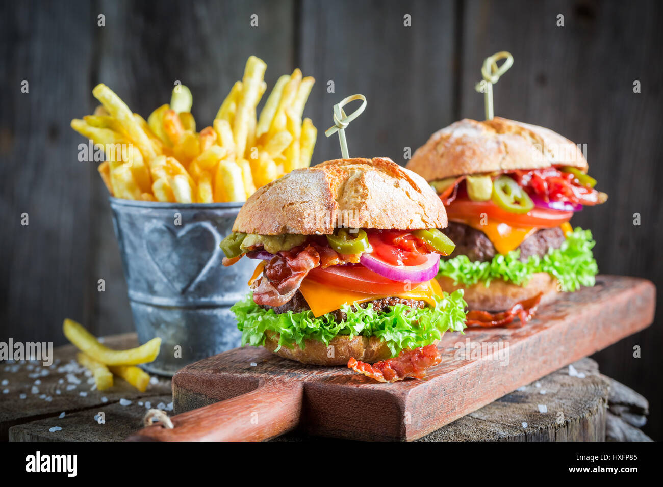 Chips and spicy burger with bacon, tomato and beef Stock Photo - Alamy