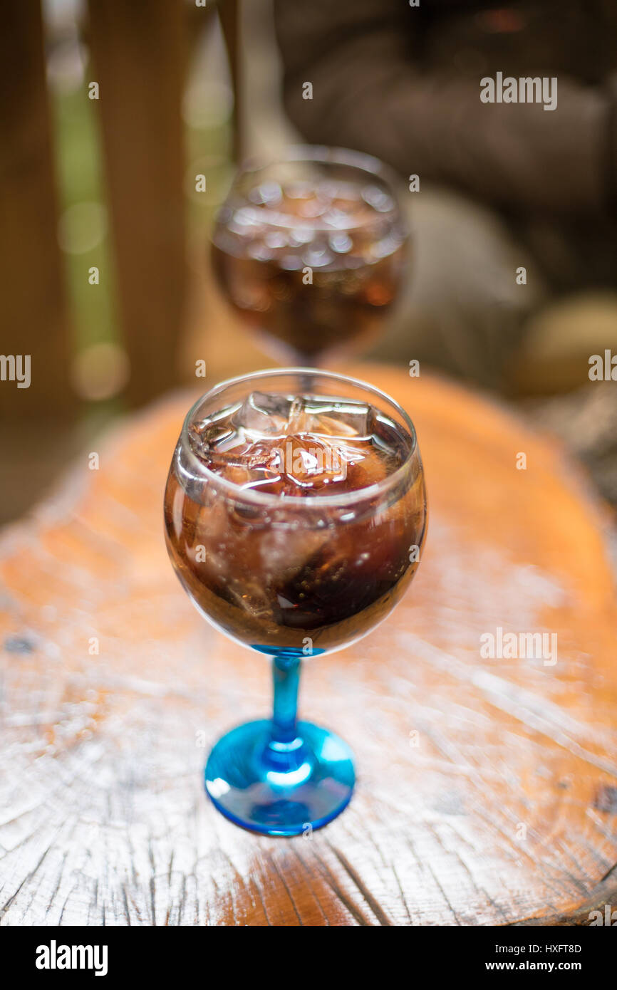 two transparent glass wide cups, with blue crystal, full of cola ...