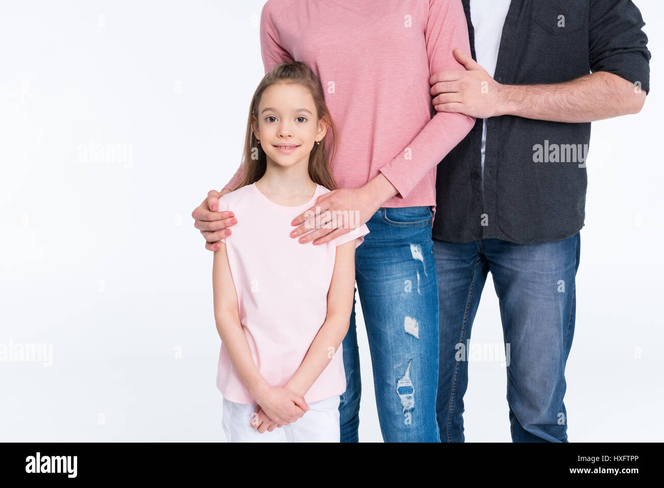 Cropped shot of young family with one child standing together on white ...