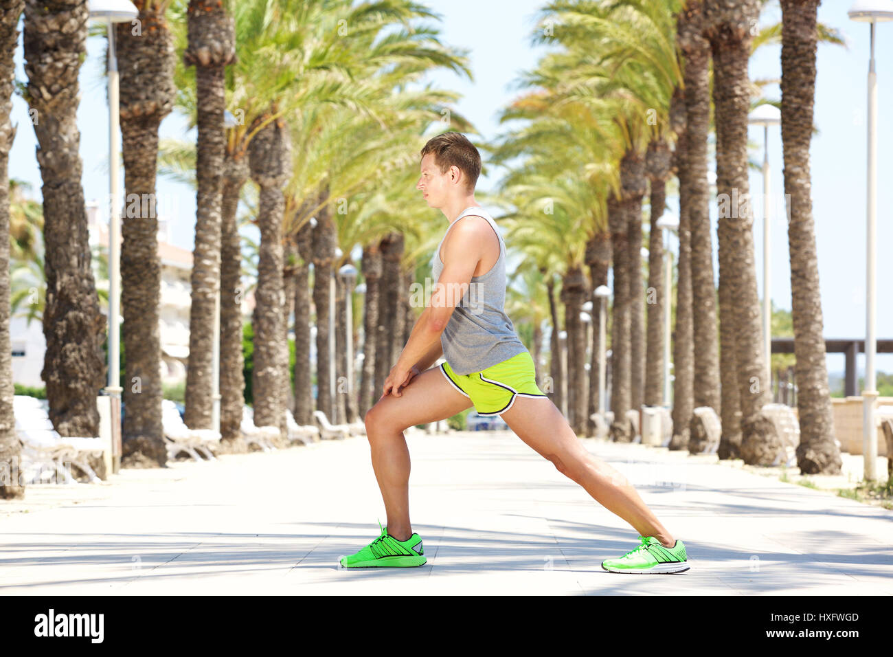 Side portrait fit young man stretching leg muscles outside Stock Photo ...