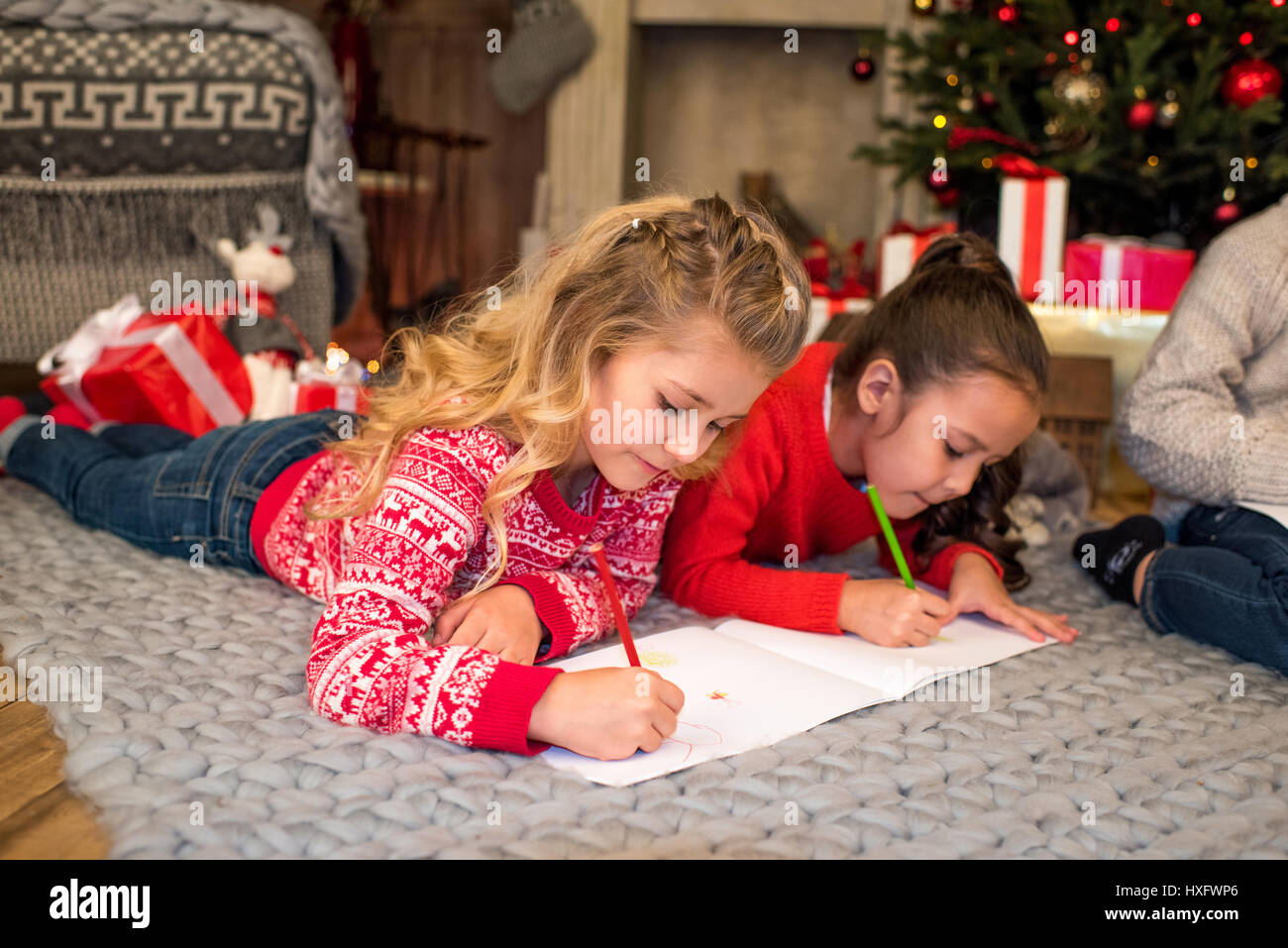 Kids lying on grey carpet and drawing picture Stock Photo - Alamy