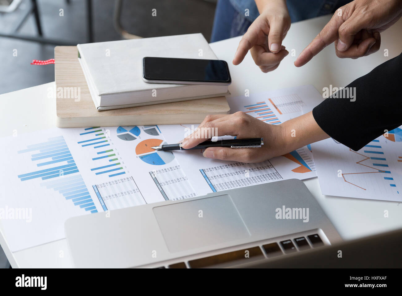 Three colleagues discussing data with new modern computer laptop on ...