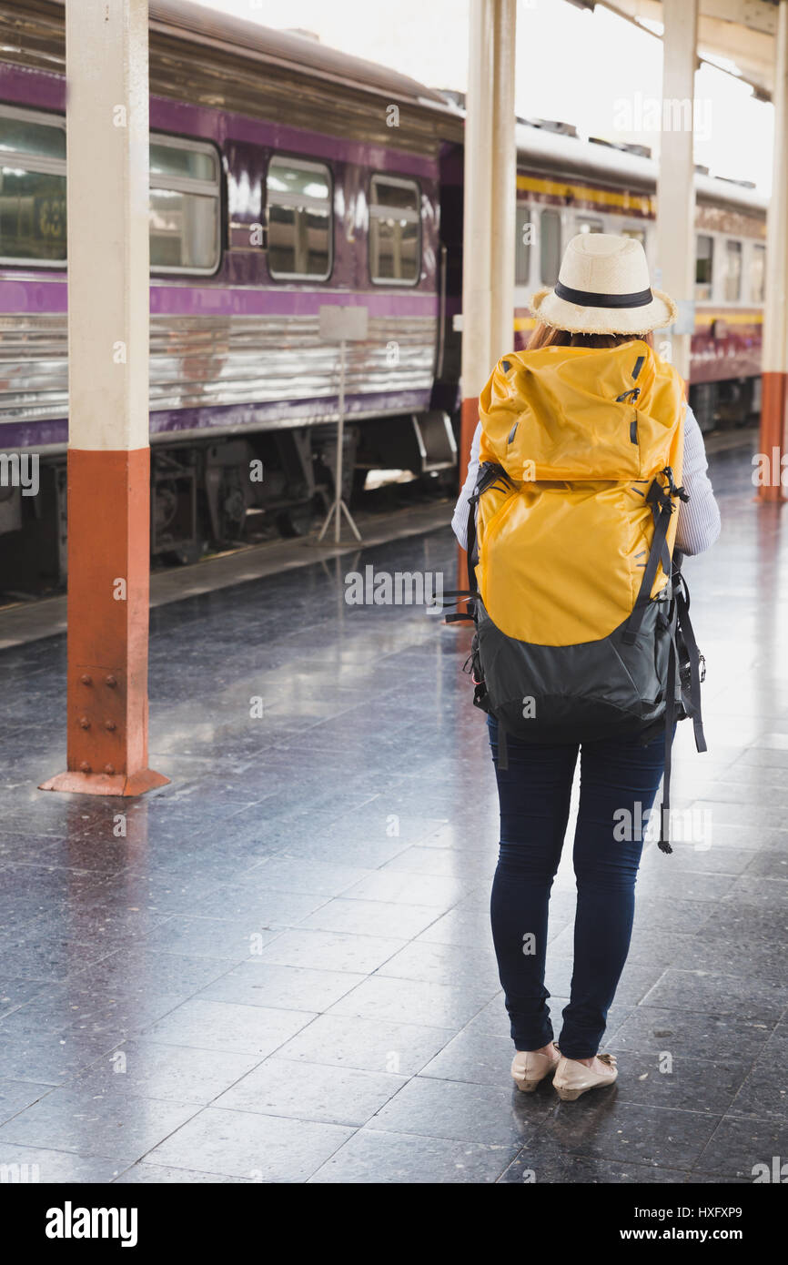 Traveler girl with a backpack waiting for train on the station. Outdoor ...