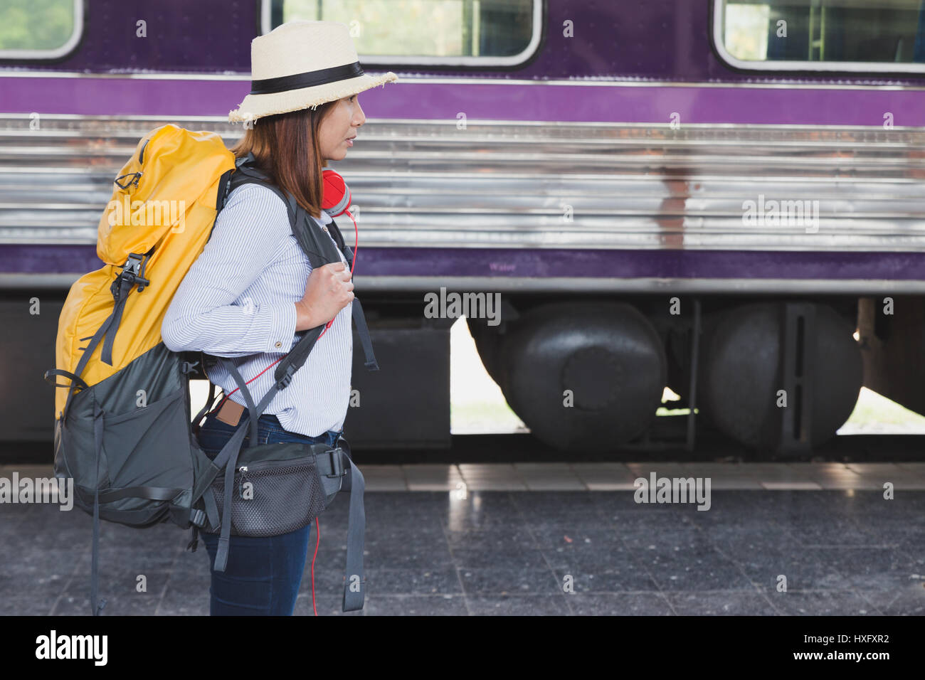 Traveler girl with a backpack waiting for train on the station. Outdoor ...