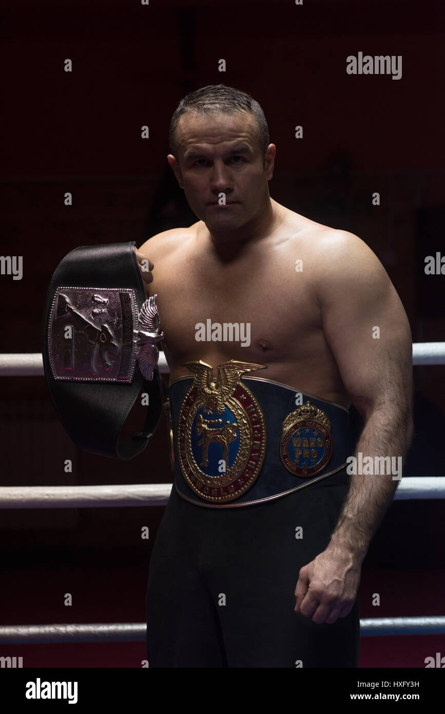portrait of muscular professional kick boxer with his championship belt ...