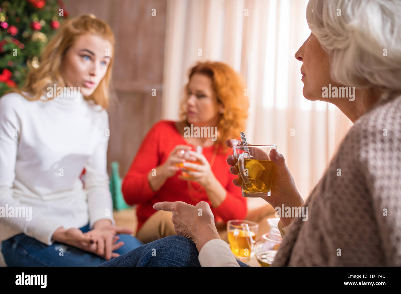 Family of three generations having tea time at home sitting on the ...
