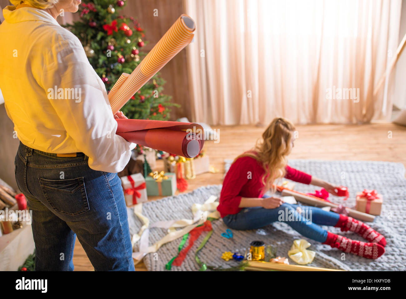 Mother and daughter with rolls of wrapping paper and unpacked christmas ...