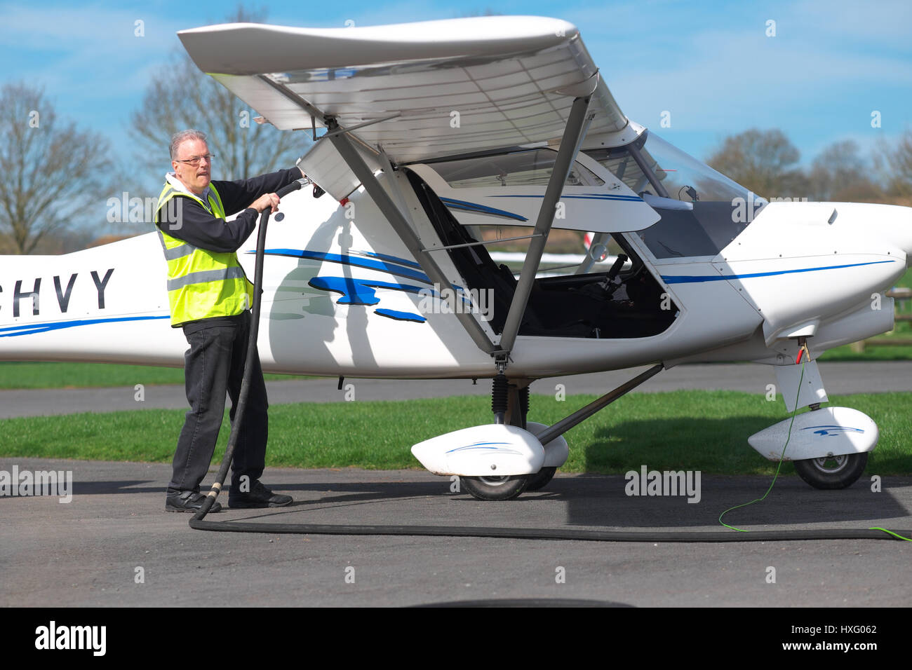 A pilot wearing a high viz jacket refuels his C42 microlight aircraft ...