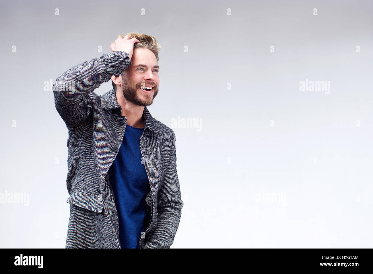 Portrait of a cool male fashion model with beard smiling with hand in ...