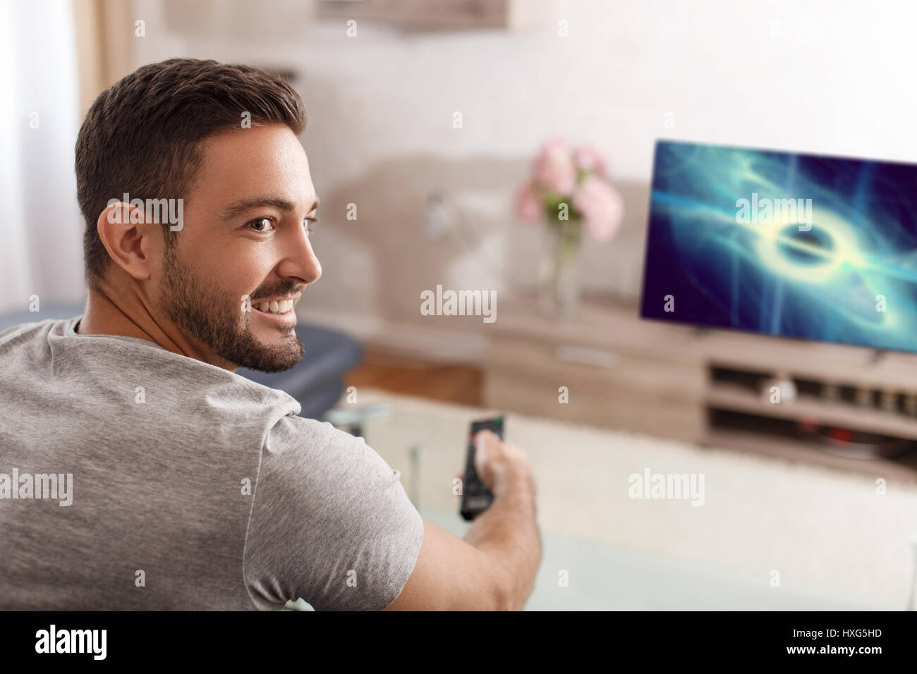 Excited man switch TV to sci-fi movie by remote control Stock Photo - Alamy