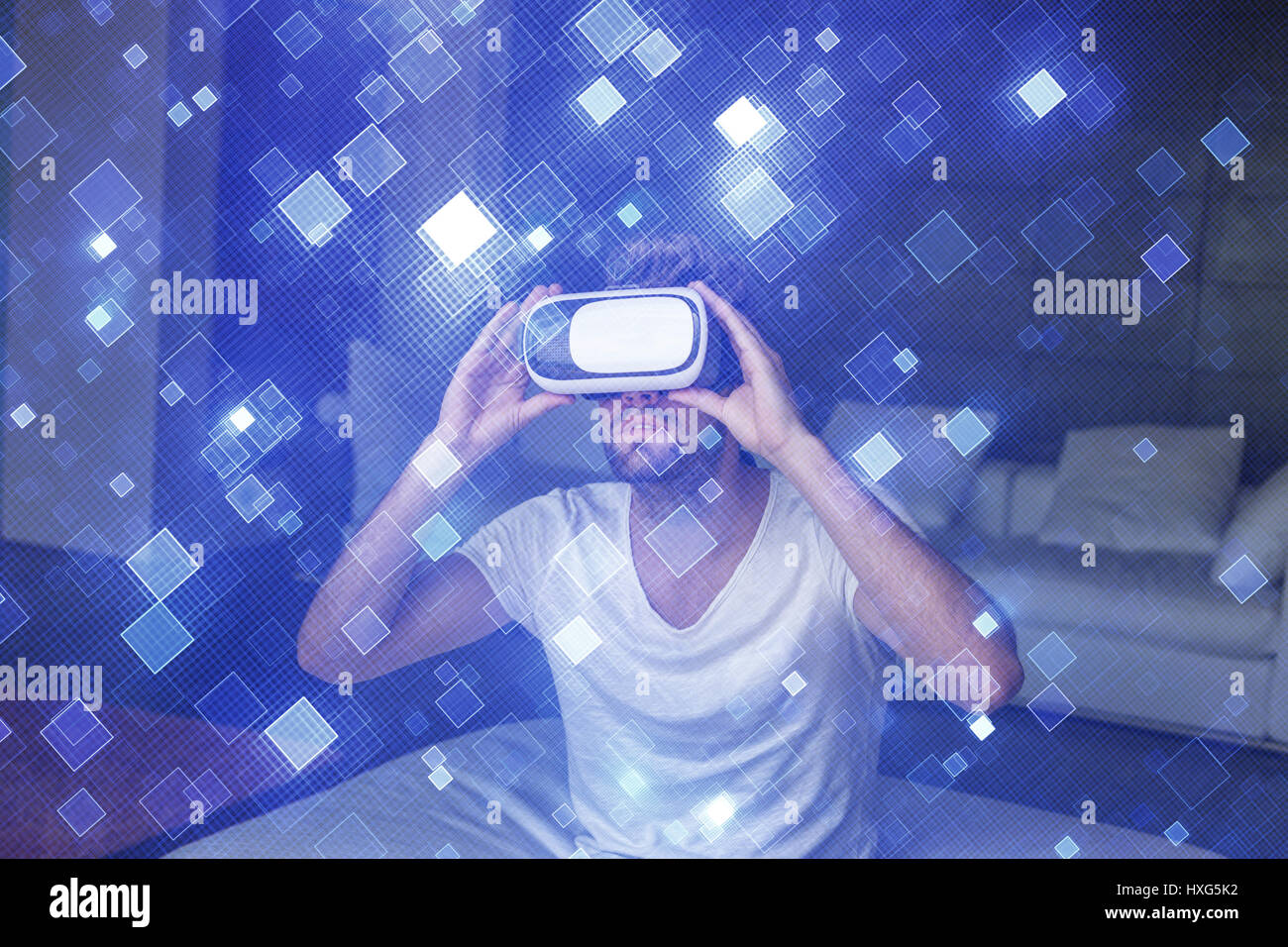 Young man with headset playing virtual reality with blue glowing square ...